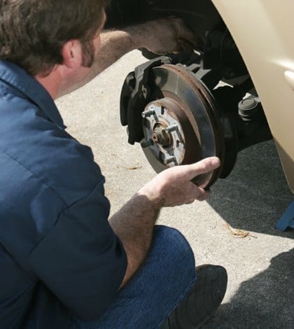 A mechanic adjusting the brakes on a car. - Today's General Counsel